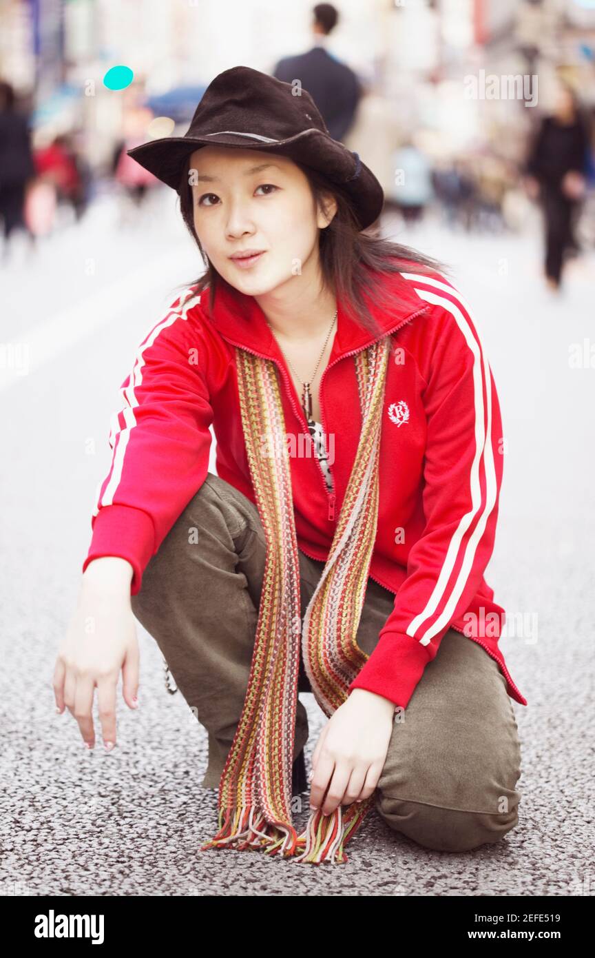 Portrait of a young woman squatting on the street Stock Photo - Alamy