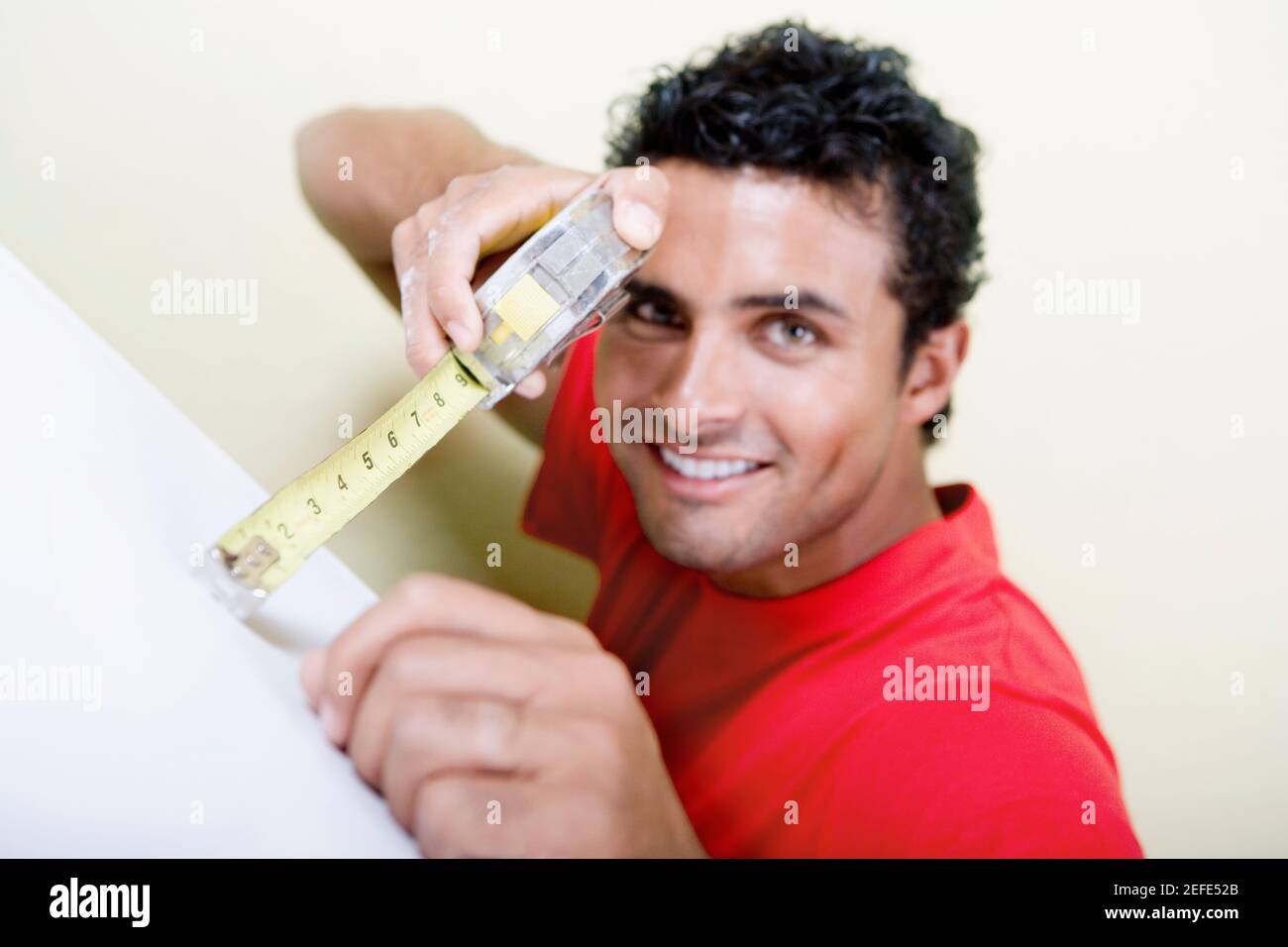 Portrait of a young man measuring with a measuring tape Stock Photo - Alamy