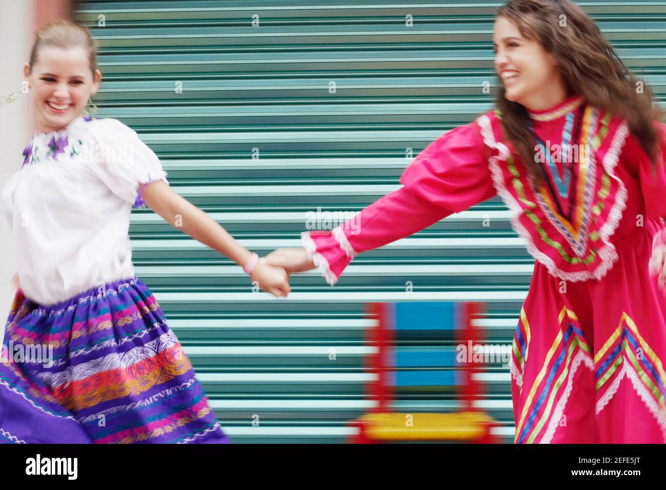 Two young women holding hands and walking Stock Photo - Alamy