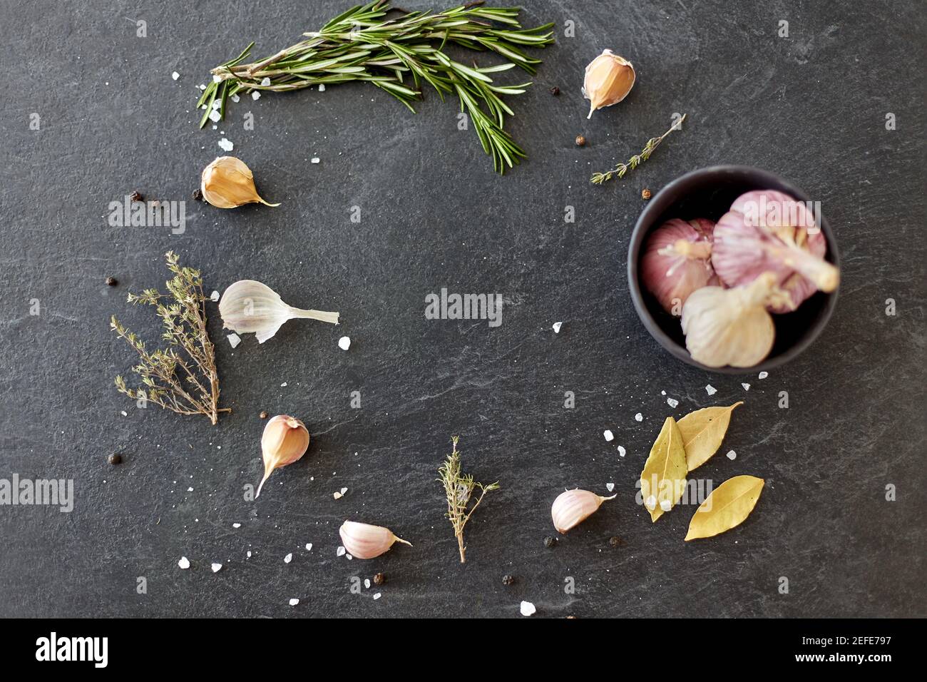 garlic in bowl and rosemary on stone surface Stock Photo - Alamy