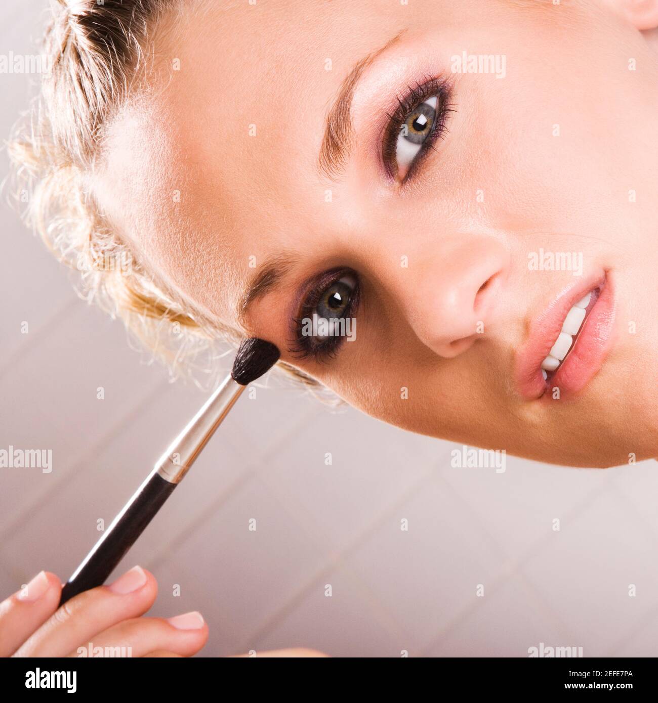 Portrait of a young woman applying eyeshadow Stock Photo - Alamy
