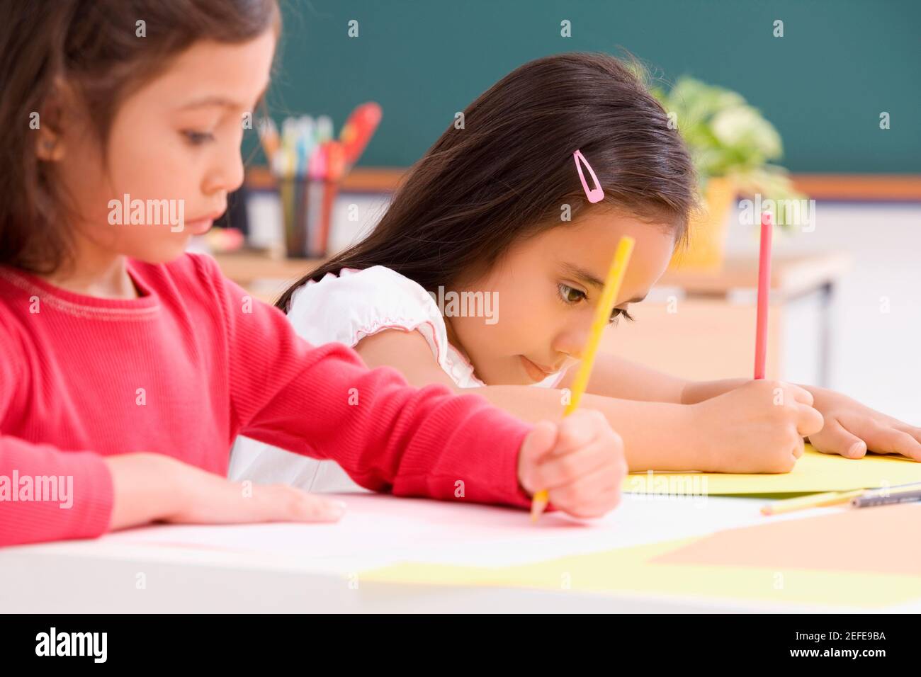 Two girls drawing in a classroom Stock Photo - Alamy