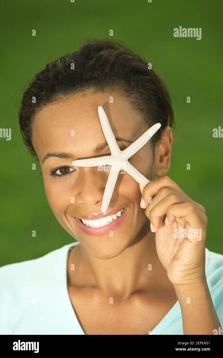 Portrait of a young woman covering her eye with a starfish Stock Photo ...
