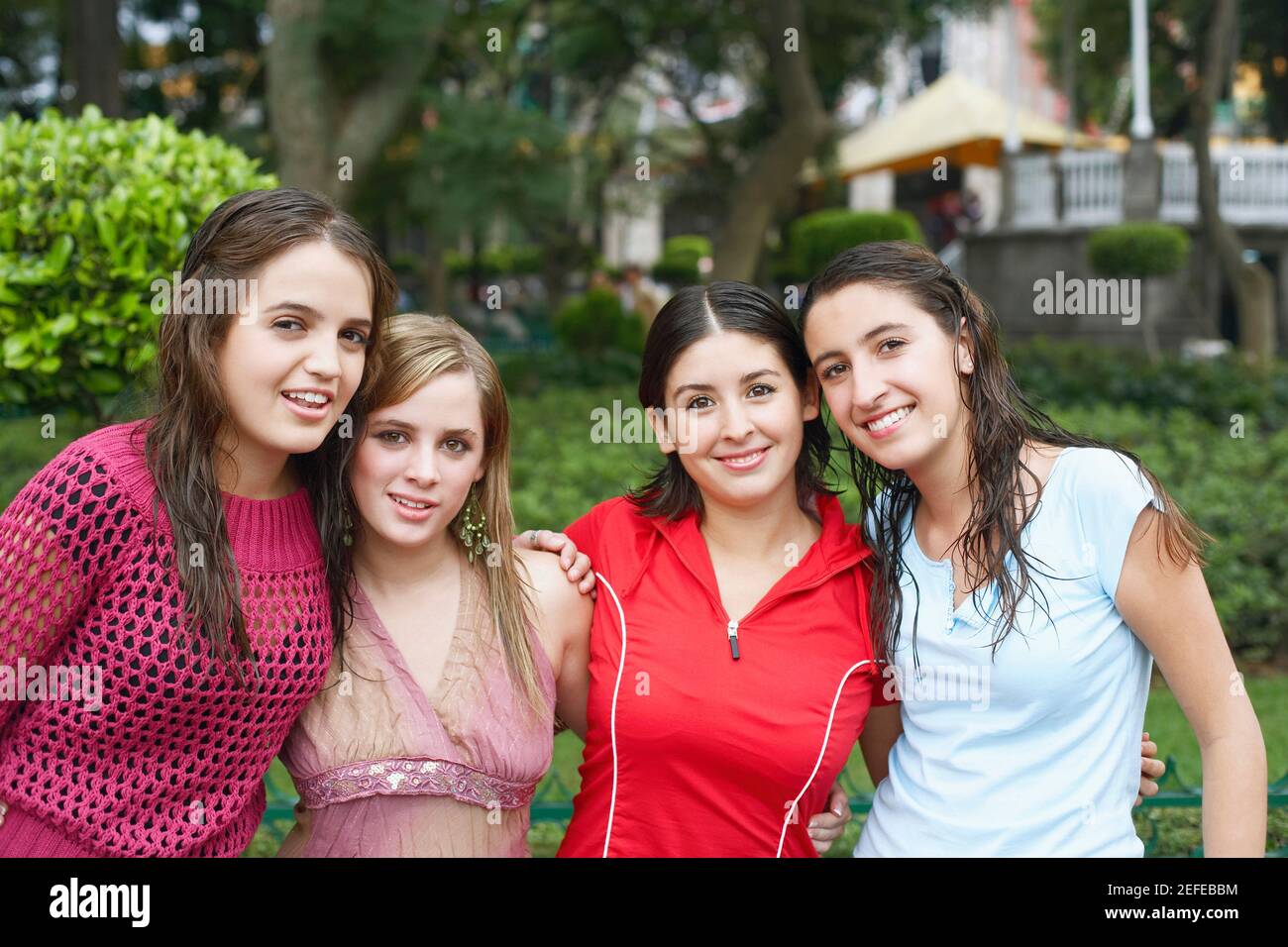 Portrait of four young women standing together and smiling Stock Photo ...