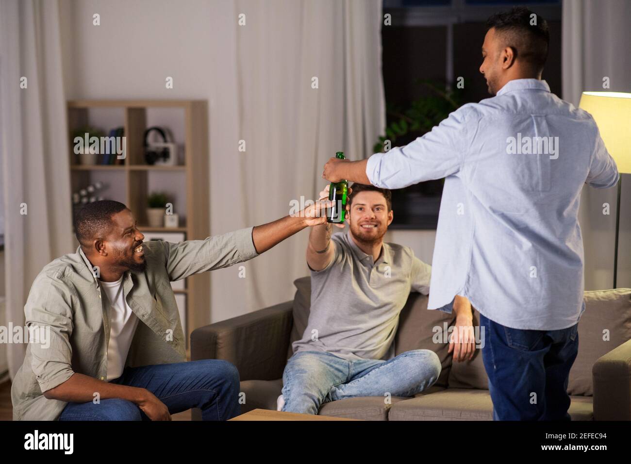 happy male friends drinking beer at home at night Stock Photo - Alamy