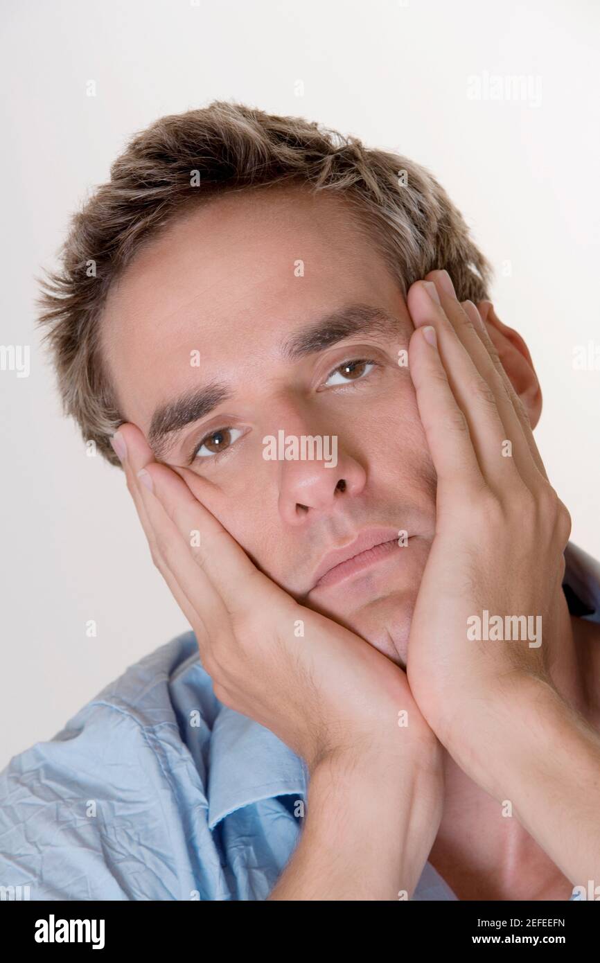 Portrait of a young man with his hands on his face Stock Photo - Alamy