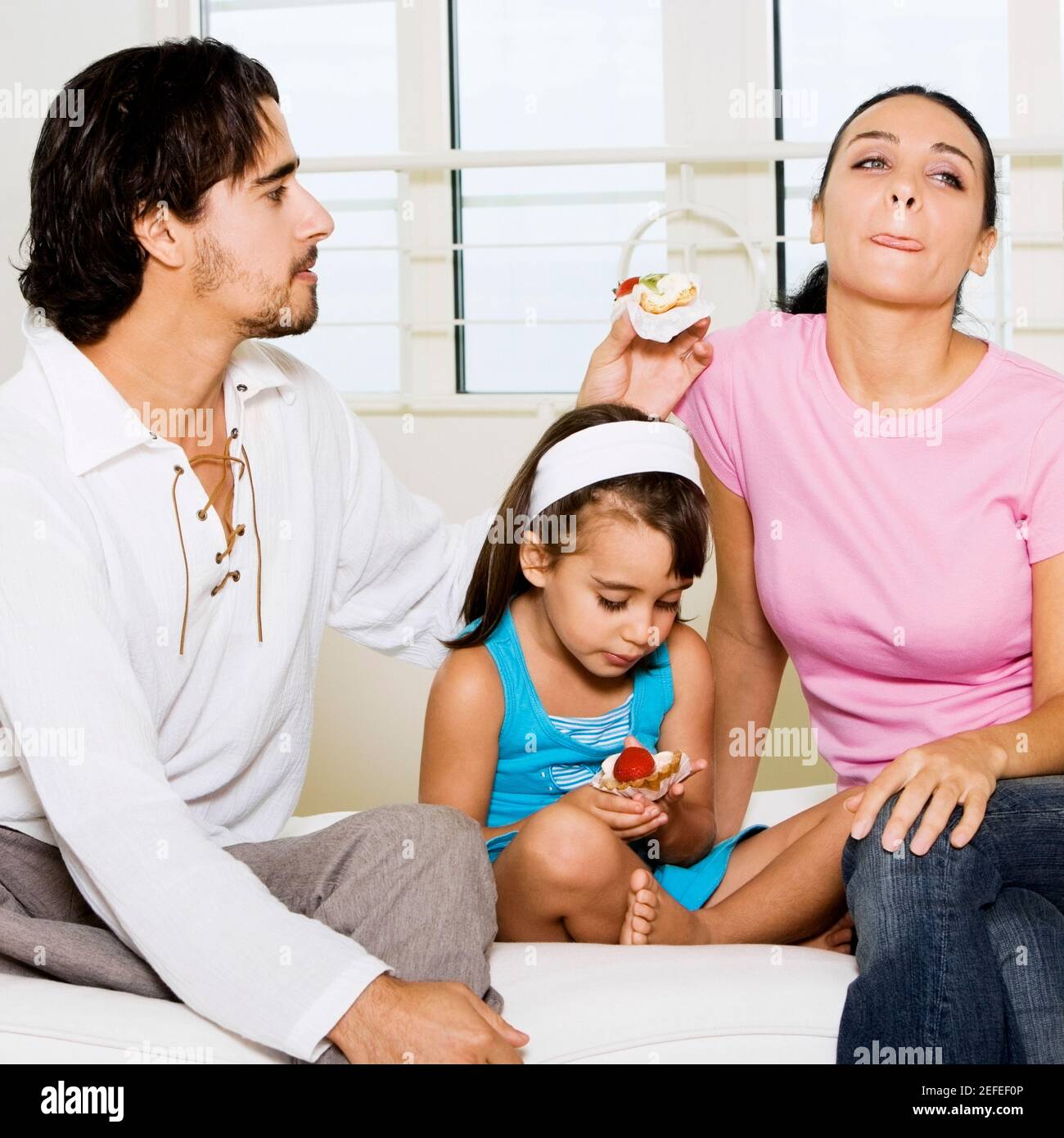 Close-up of a young couple and their daughter eating a pastry Stock ...