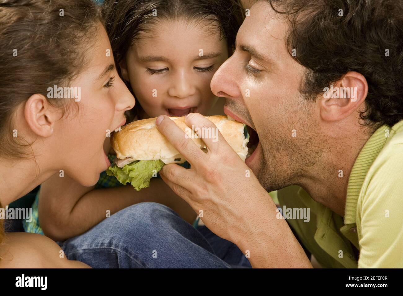Side profile of parents and their daughter eating a burger Stock Photo ...