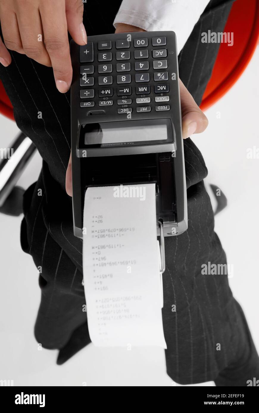 Mid section view of a businesswoman holding an adding machine tape ...