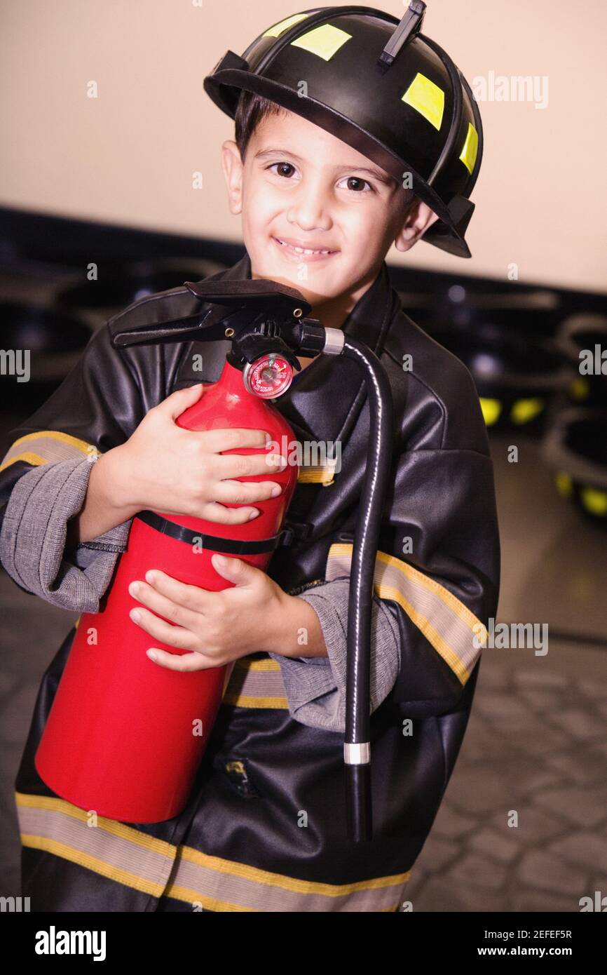 Portrait of a boy dressed as a firefighter and holding a fire ...
