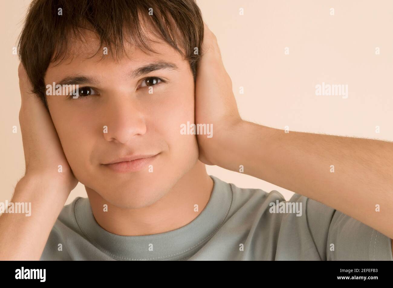 Portrait of a young man covering his ears with his hands Stock Photo ...