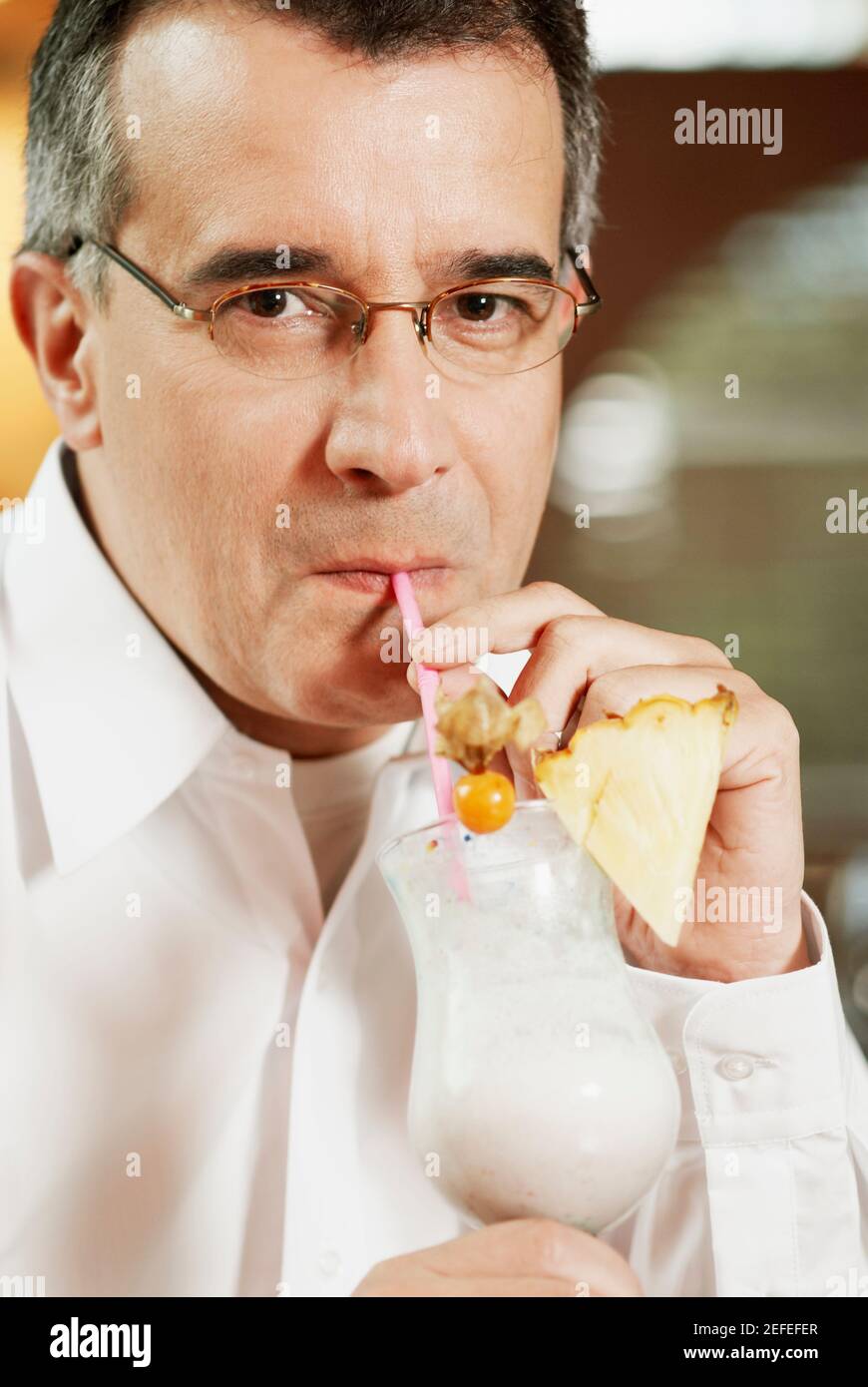 Portrait of a mid adult man drinking pina colada with a drinking straw ...