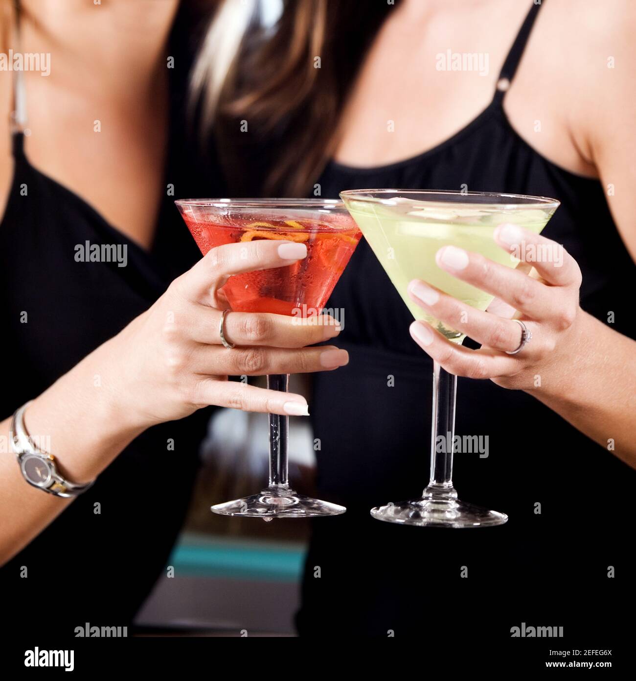 Mid section view of two young women toasting martinis Stock Photo - Alamy