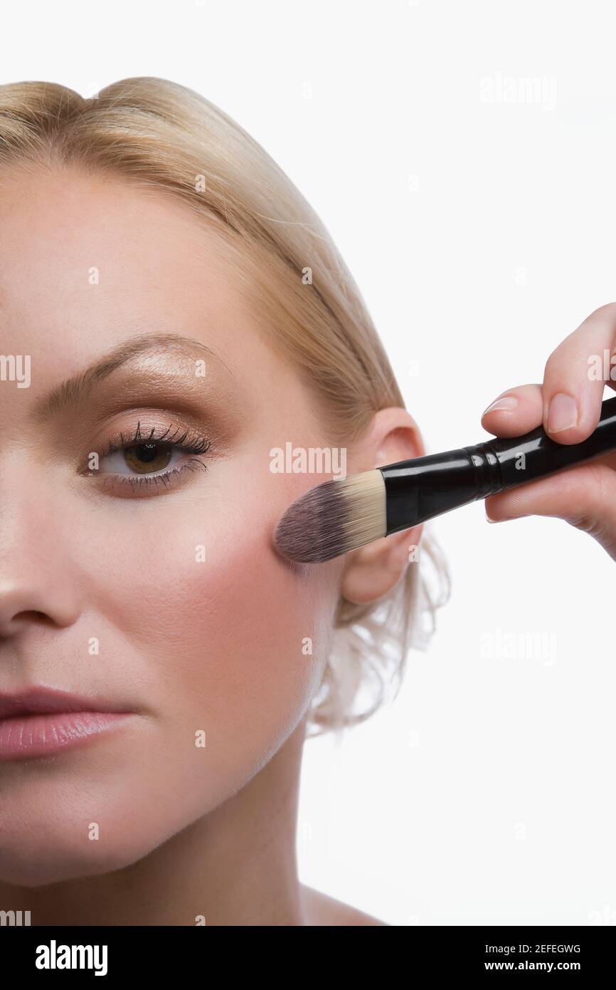 Portrait of a young woman applying blush on her cheek Stock Photo - Alamy