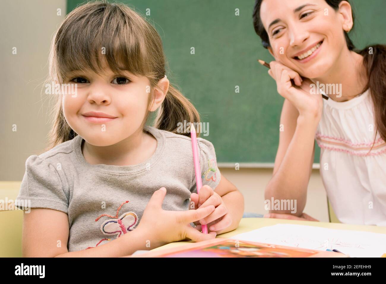 Portrait of a girl smirking with her teacher in the background Stock ...