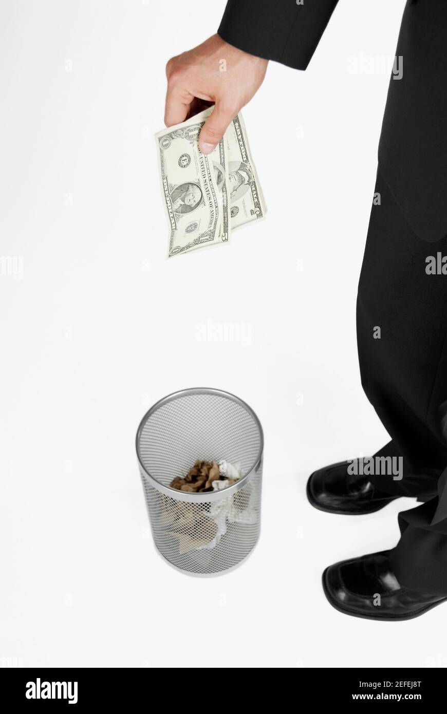 Low section view of a businessman throwing paper currency into a ...