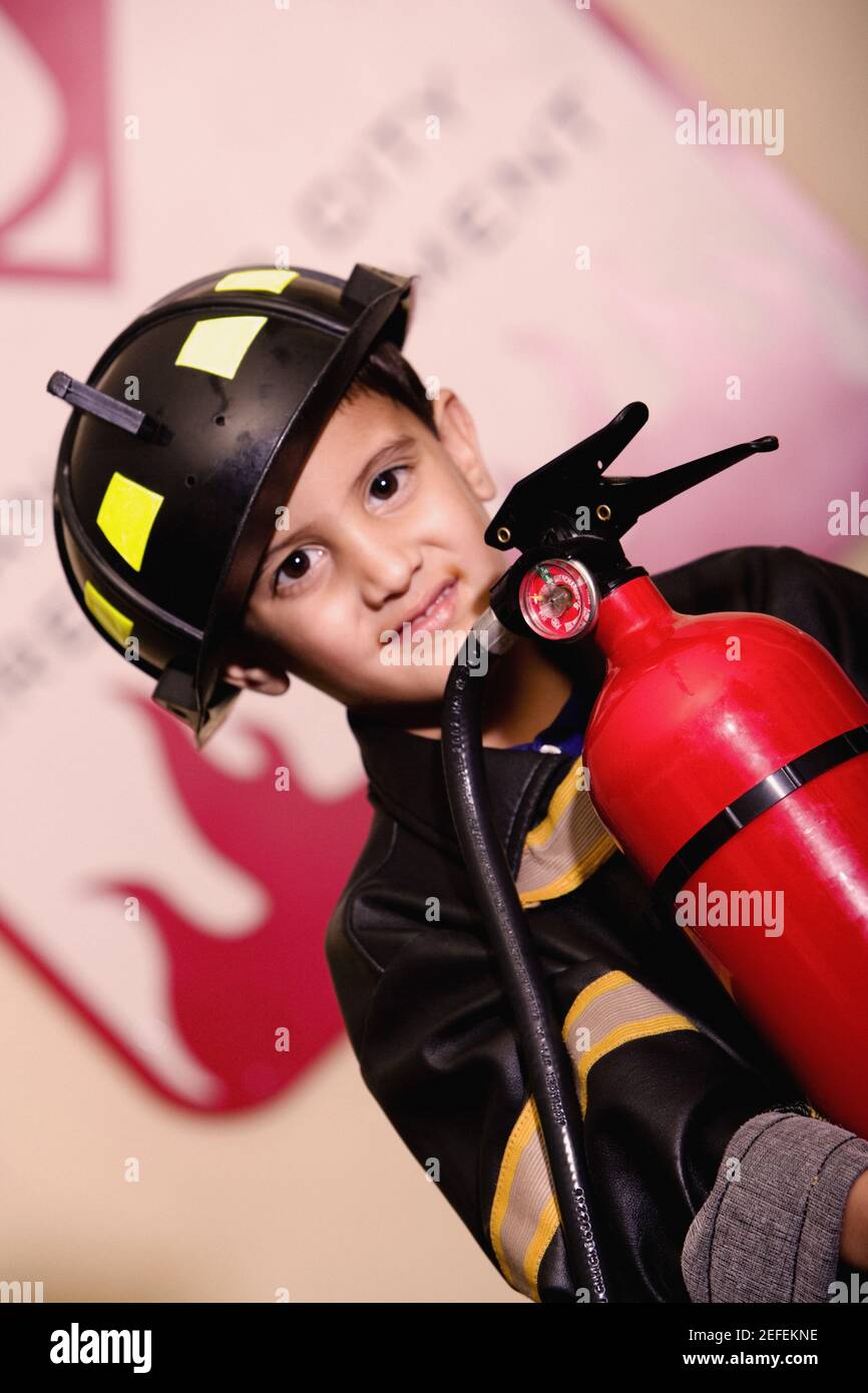 Portrait of a boy dressed as a firefighter and holding a fire ...
