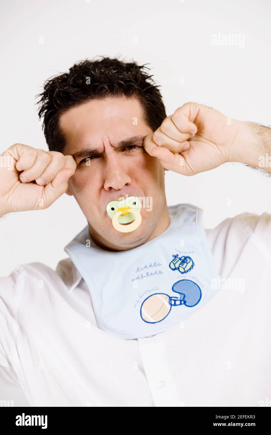 Portrait of a mid adult man sucking a pacifier and imitating a baby ...