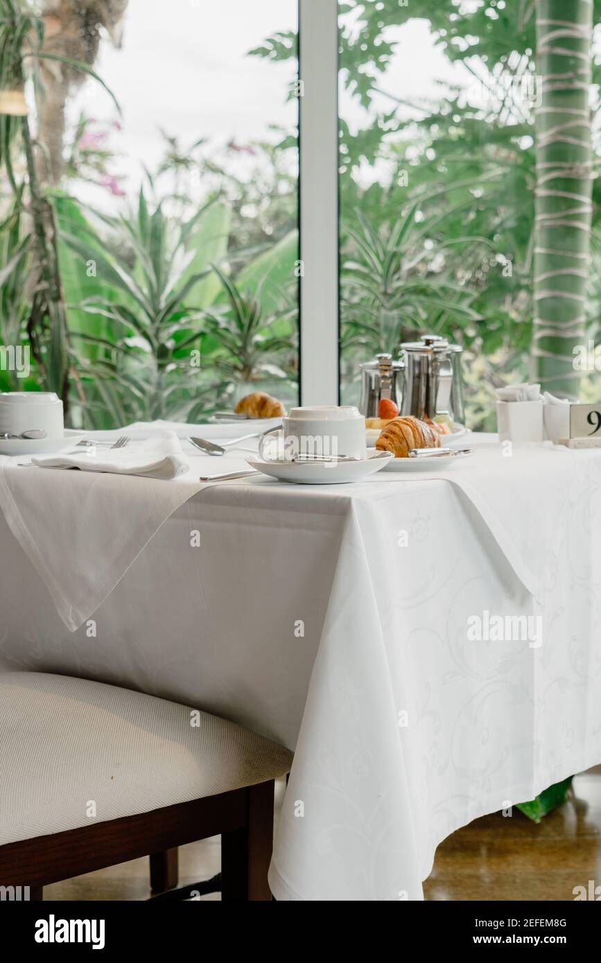 Served table for breakfast against the background of a large window ...