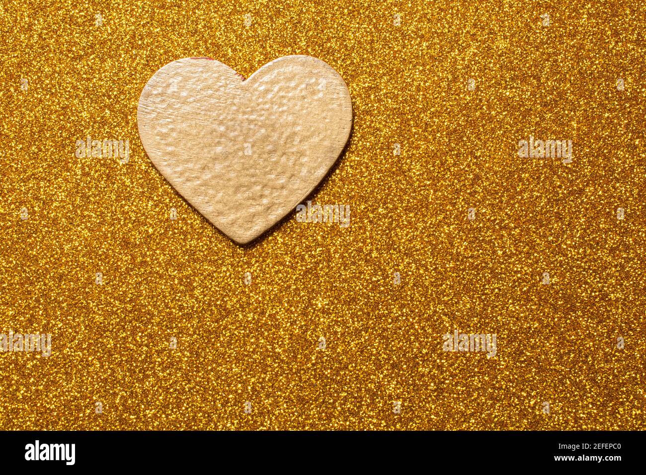 Beige heart-shaped figure isolated on the golden glitter background ...