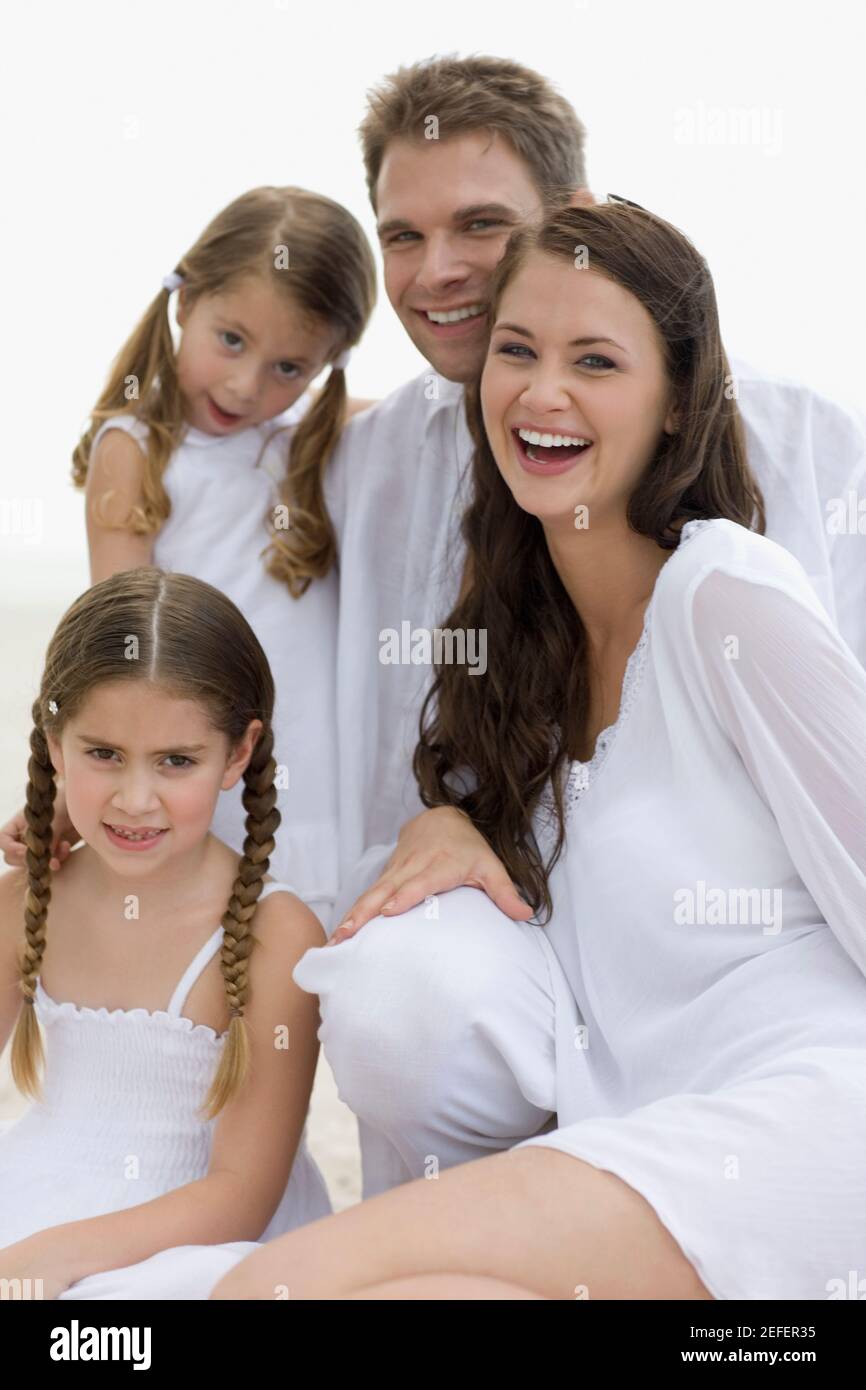Portrait of a young couple and their two daughters smiling Stock Photo ...