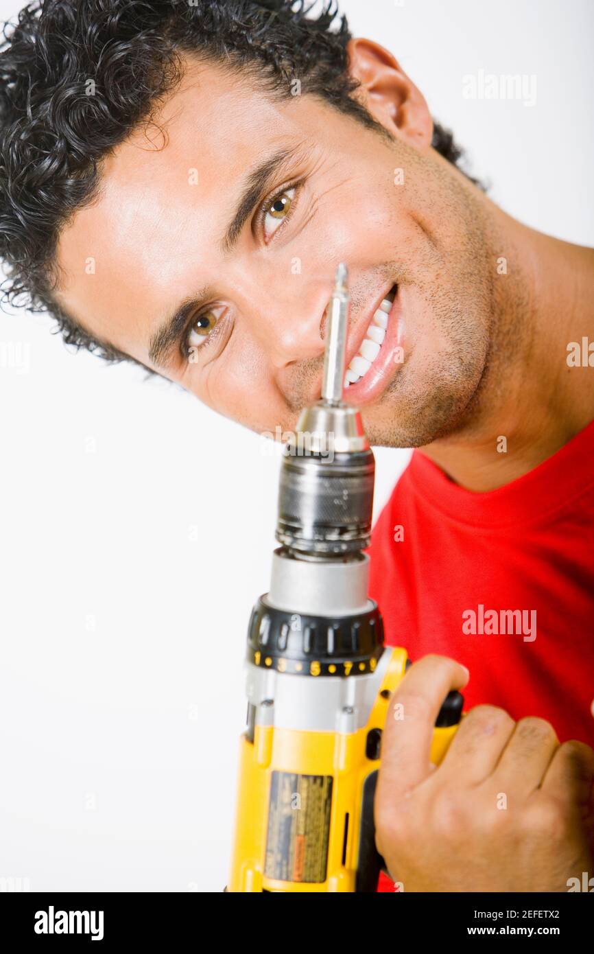 Portrait of a young man holding a drill machine and smiling Stock Photo ...