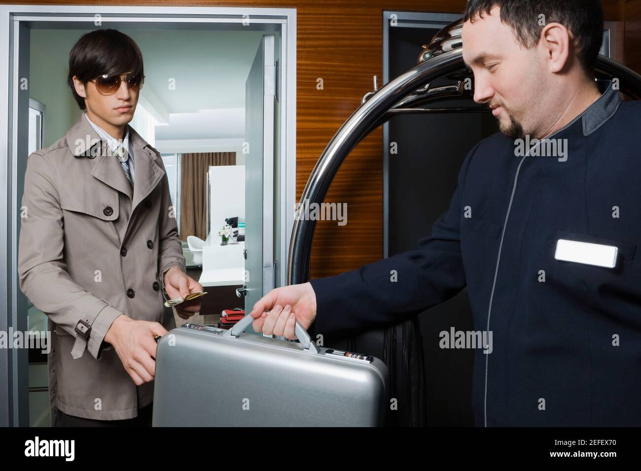 Room service man handing over a briefcase to a businessman Stock Photo ...