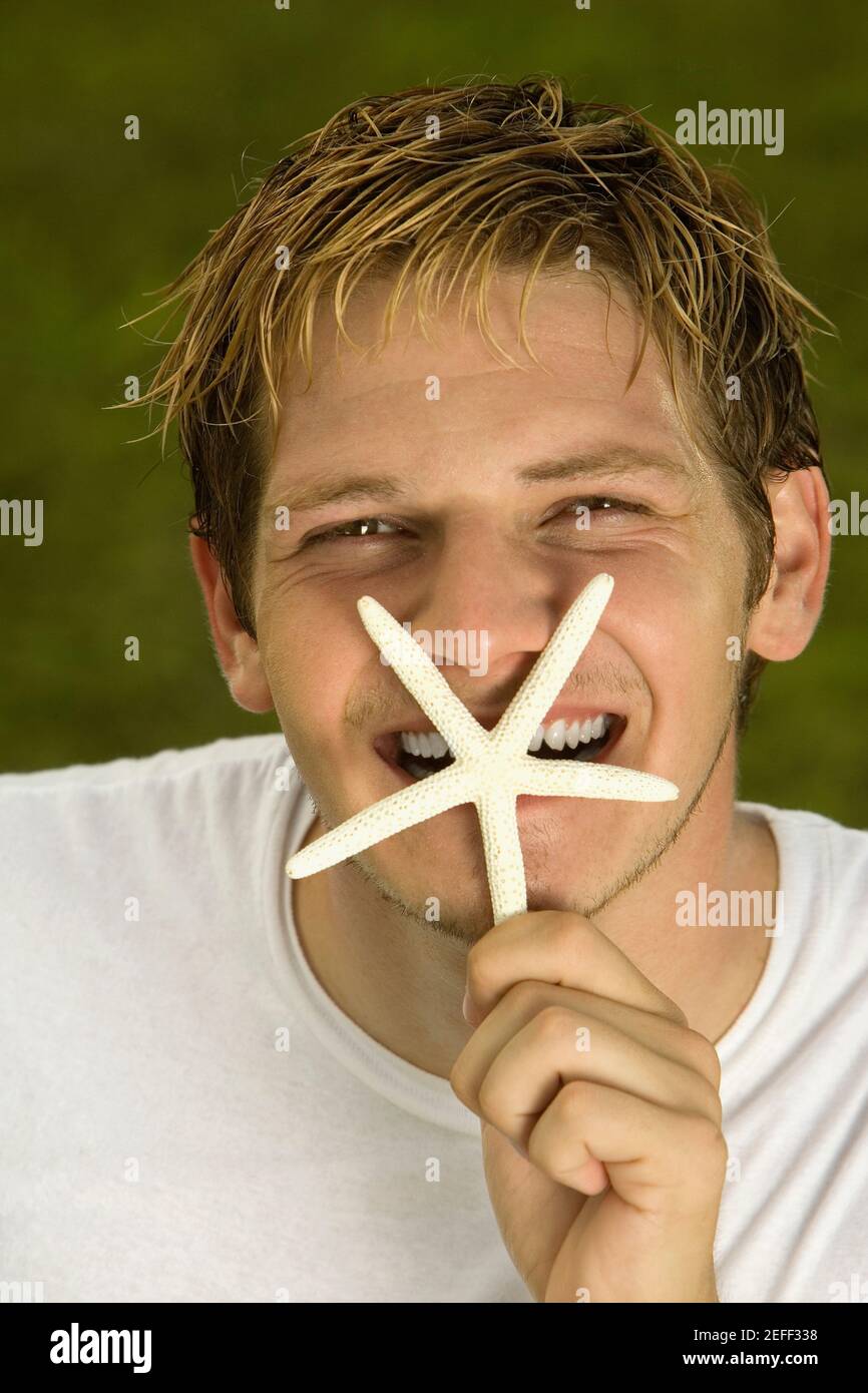 Portrait of a young man holding a starfish in front of his mouth Stock ...