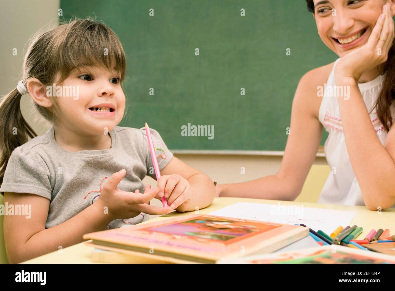 Female teacher smiling with her student sitting beside her Stock Photo ...