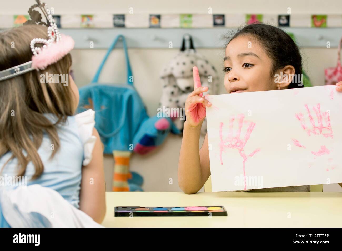 Girl showing a drawing to her classmate Stock Photo - Alamy