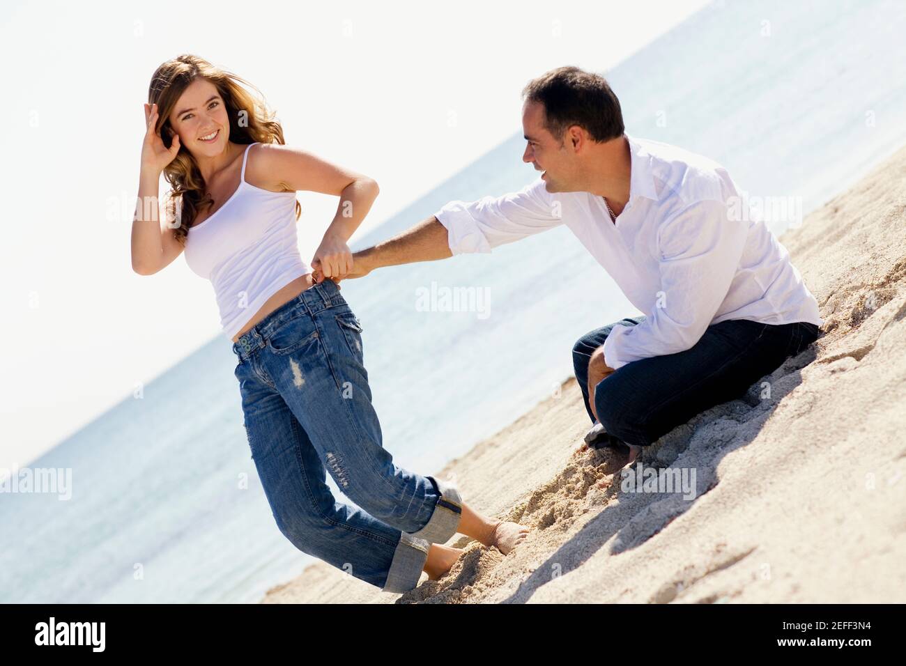 Portrait of a young woman and a mid adult man romancing on the beach ...