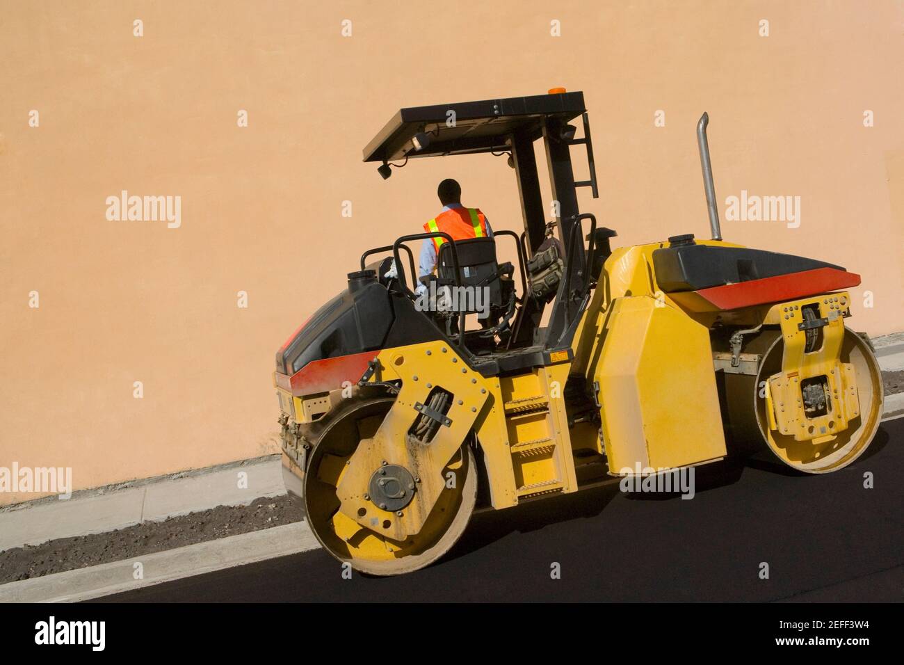 Rear view of a man sitting on a steamroller Stock Photo - Alamy