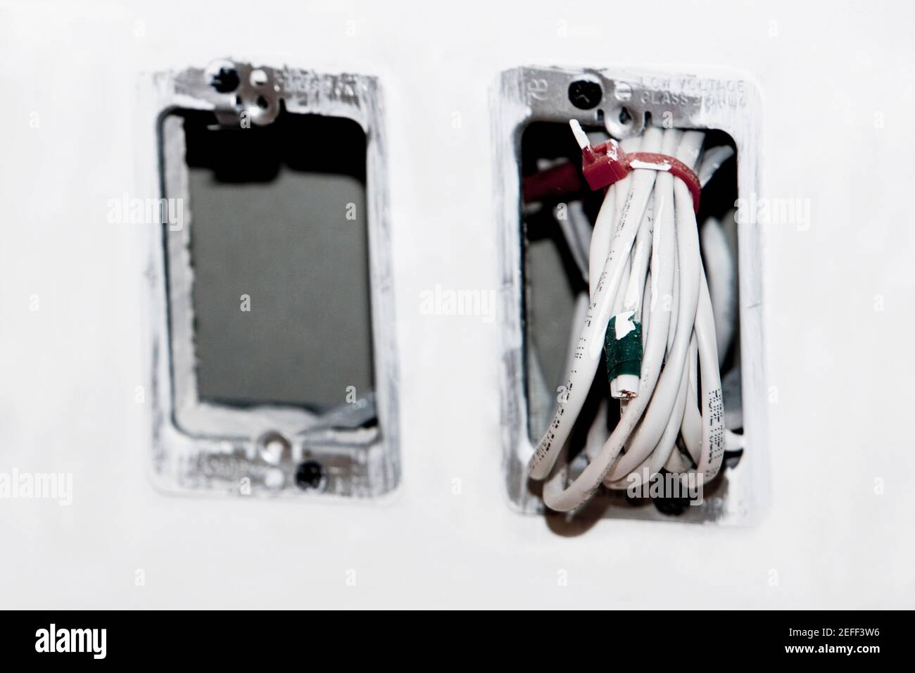 Close-up of a roll of cables coming out from a wall Stock Photo - Alamy