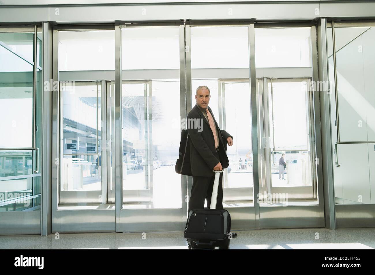 Side profile of a businessman pulling his luggage at an airport Stock ...