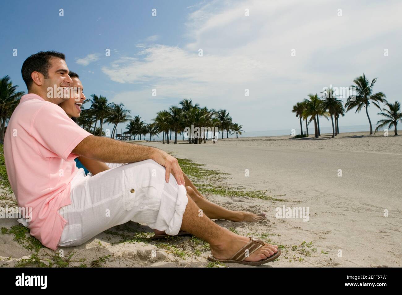 Side profile of a young couple smiling and sitting together on the ...