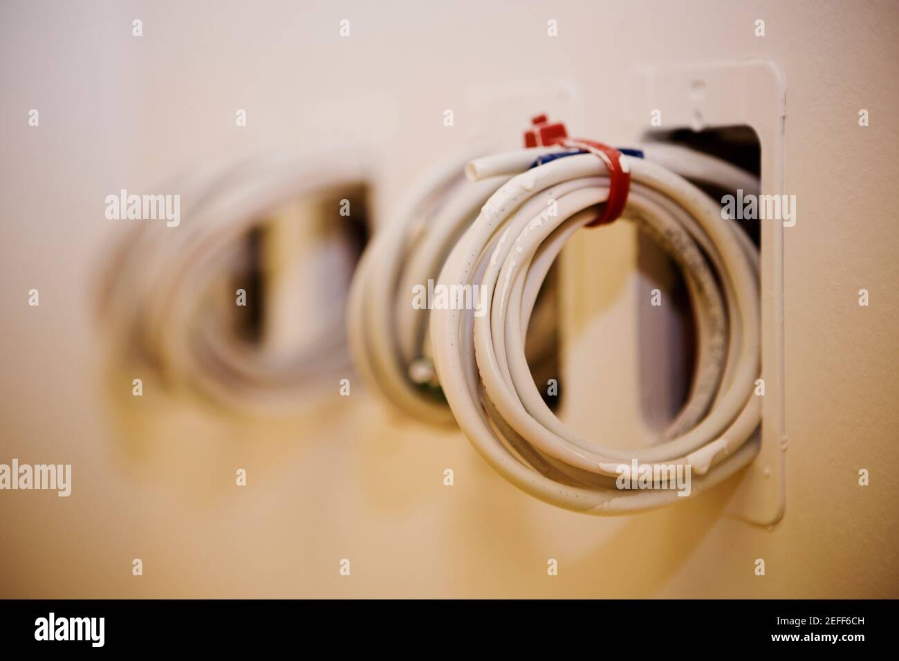 Close-up of a roll of cables coming out from a wall Stock Photo - Alamy