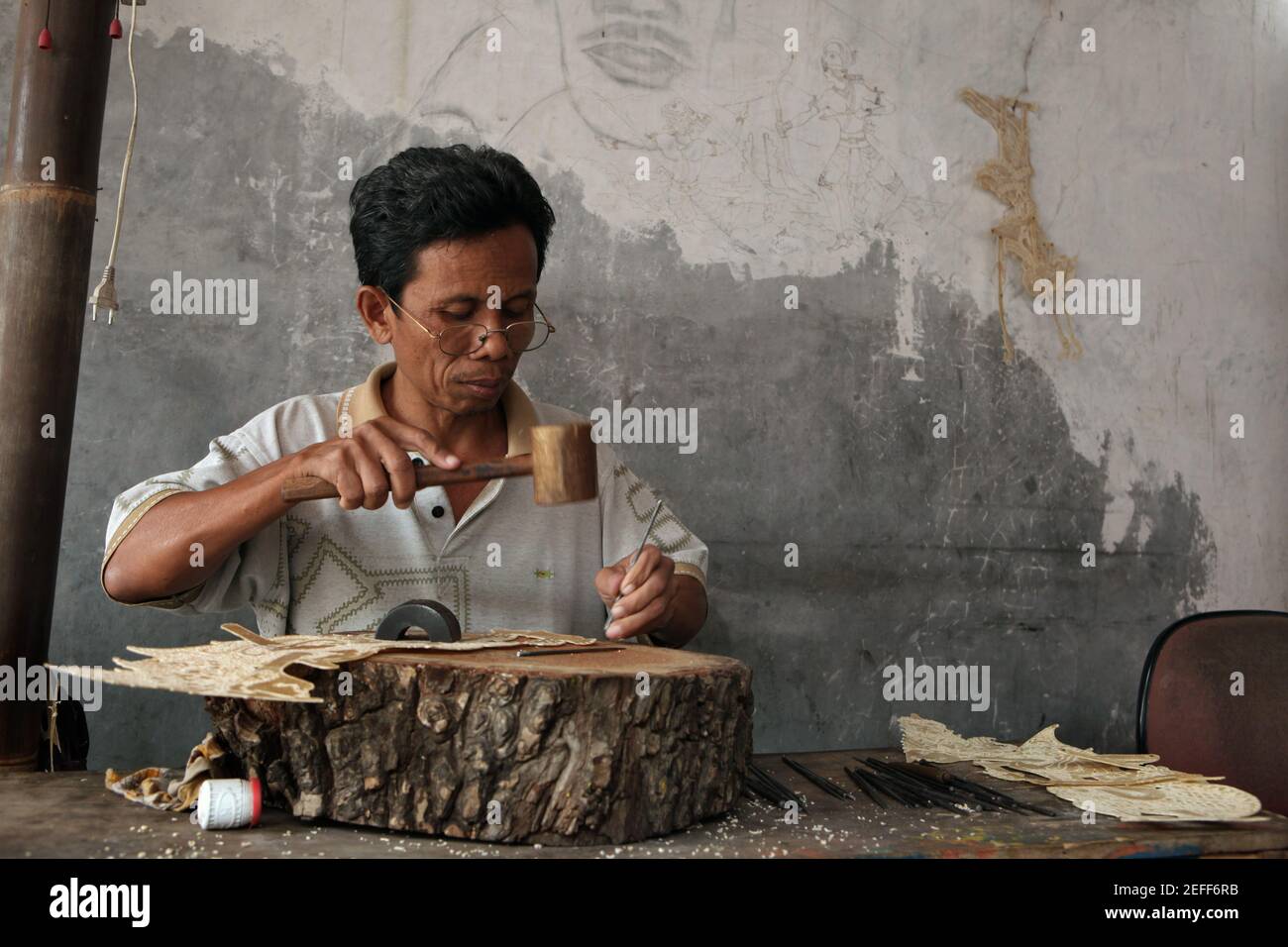 Craftsman makes a leather puppet for wayang kulit theatre in the ...