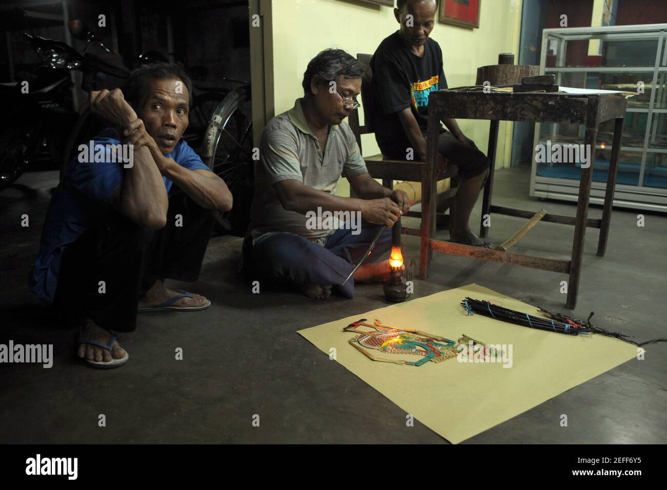 Craftsman fastens sticks of buffalo horns to the wayang kulit puppet of ...