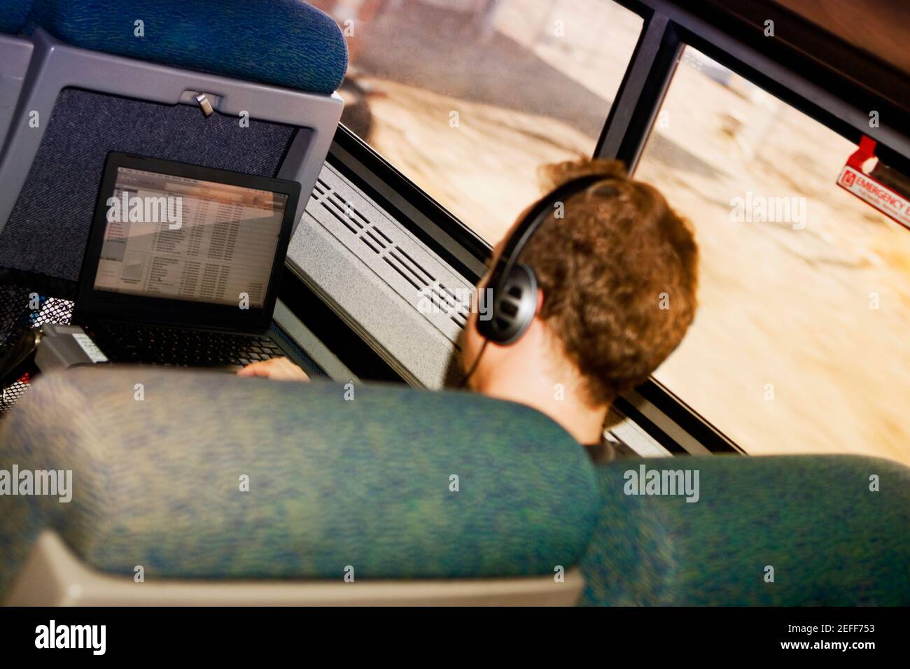 Man in a train using a laptop and listening to music in a train Stock ...
