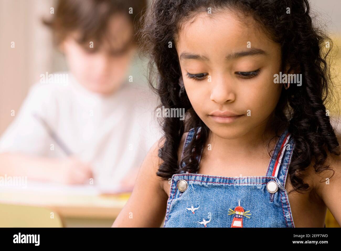Close up of a girl looking down with a boy sitting behind her Stock ...