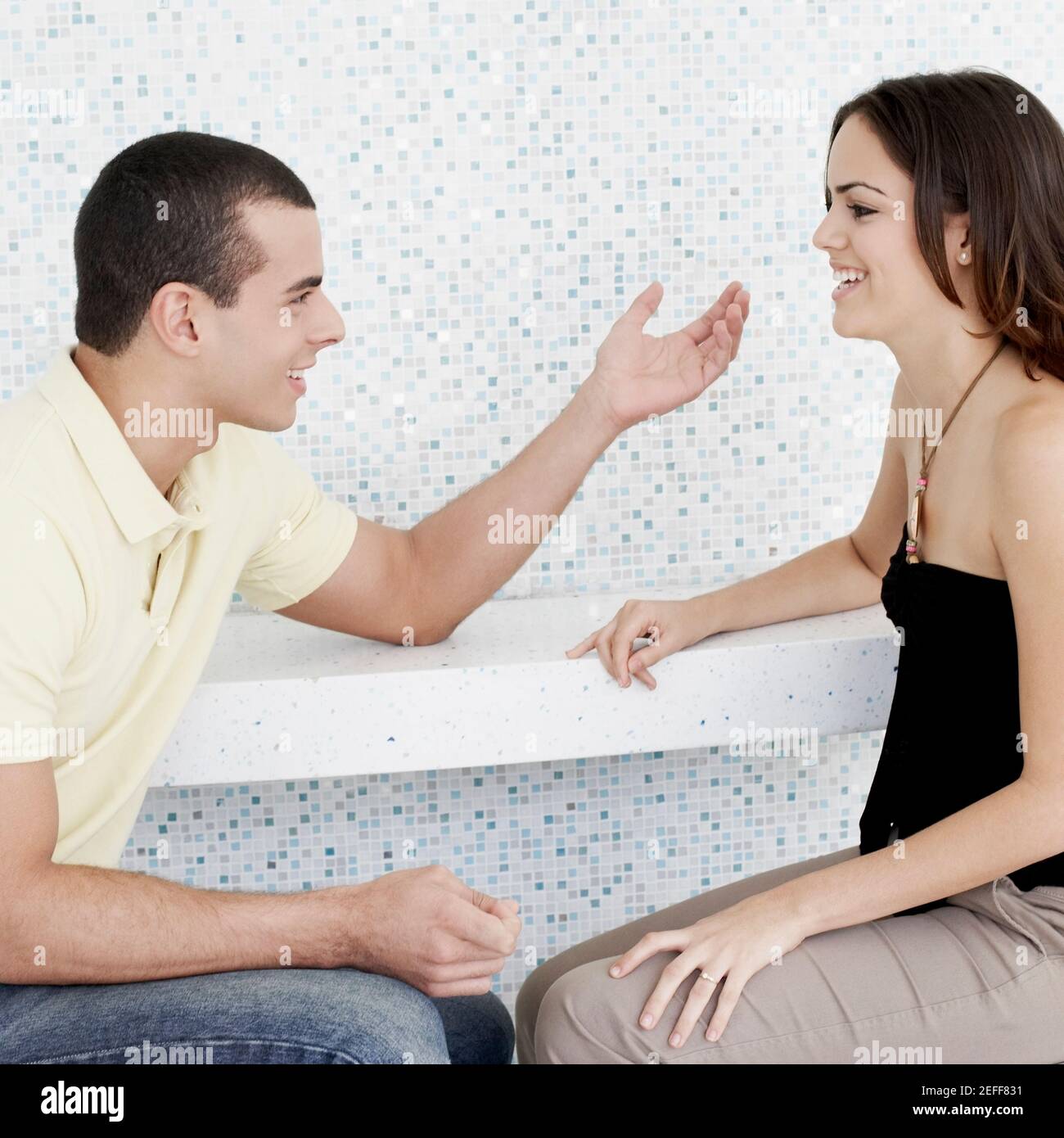 Side profile of a young couple talking to each other Stock Photo - Alamy