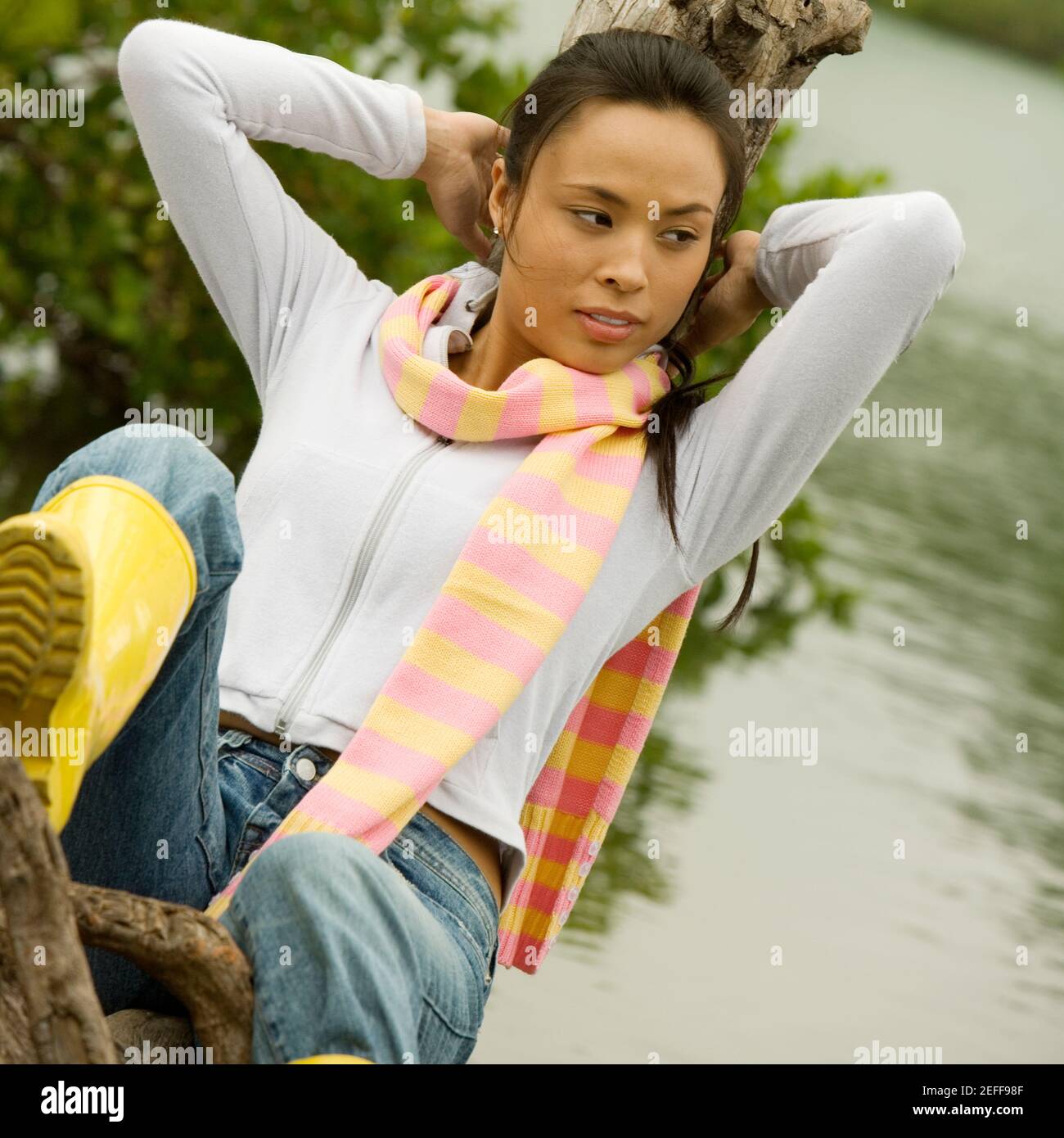 Young woman leaning against a tree stump looking away Stock Photo - Alamy