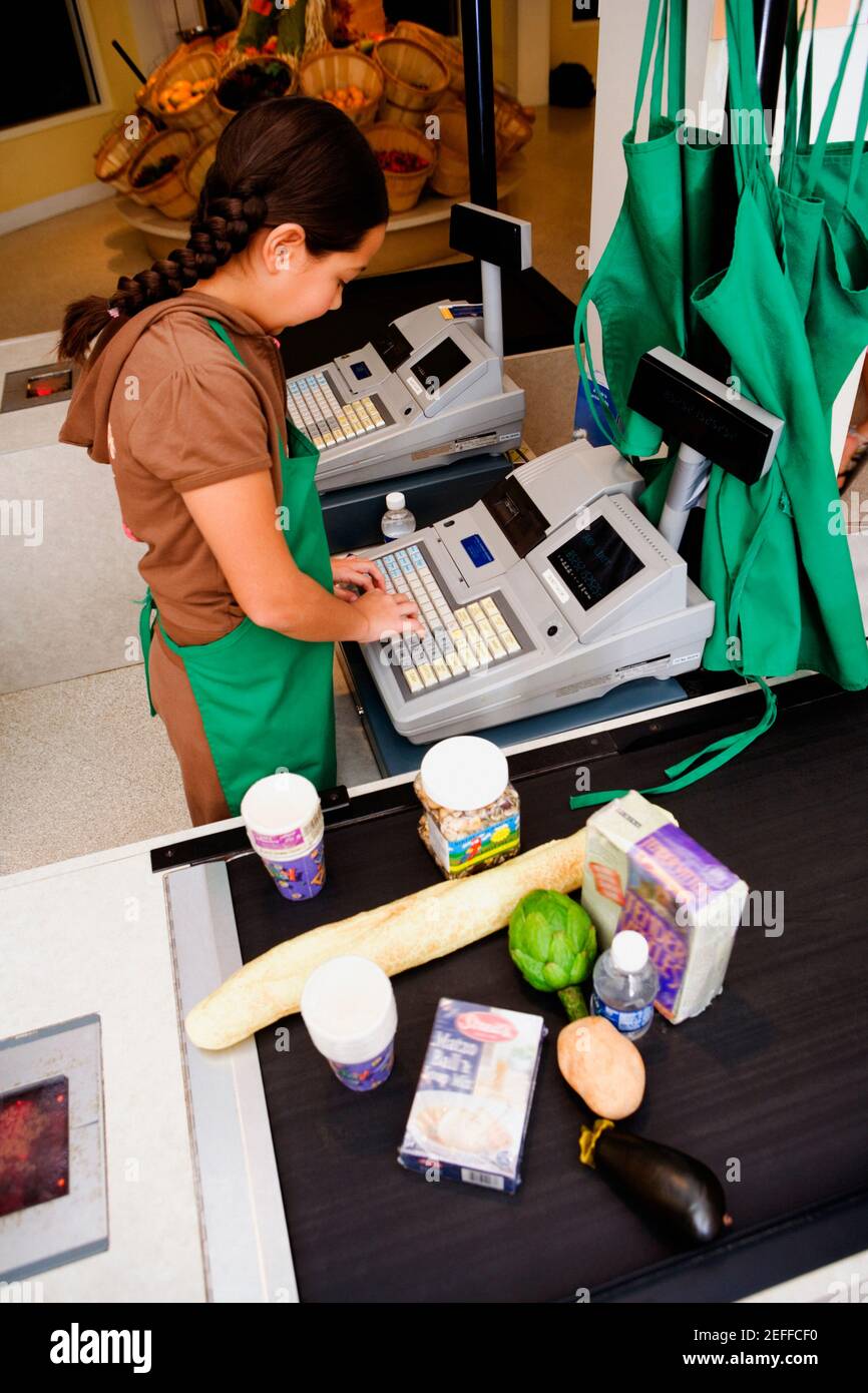 Side profile of a girl using a cash register at the checkout counter ...