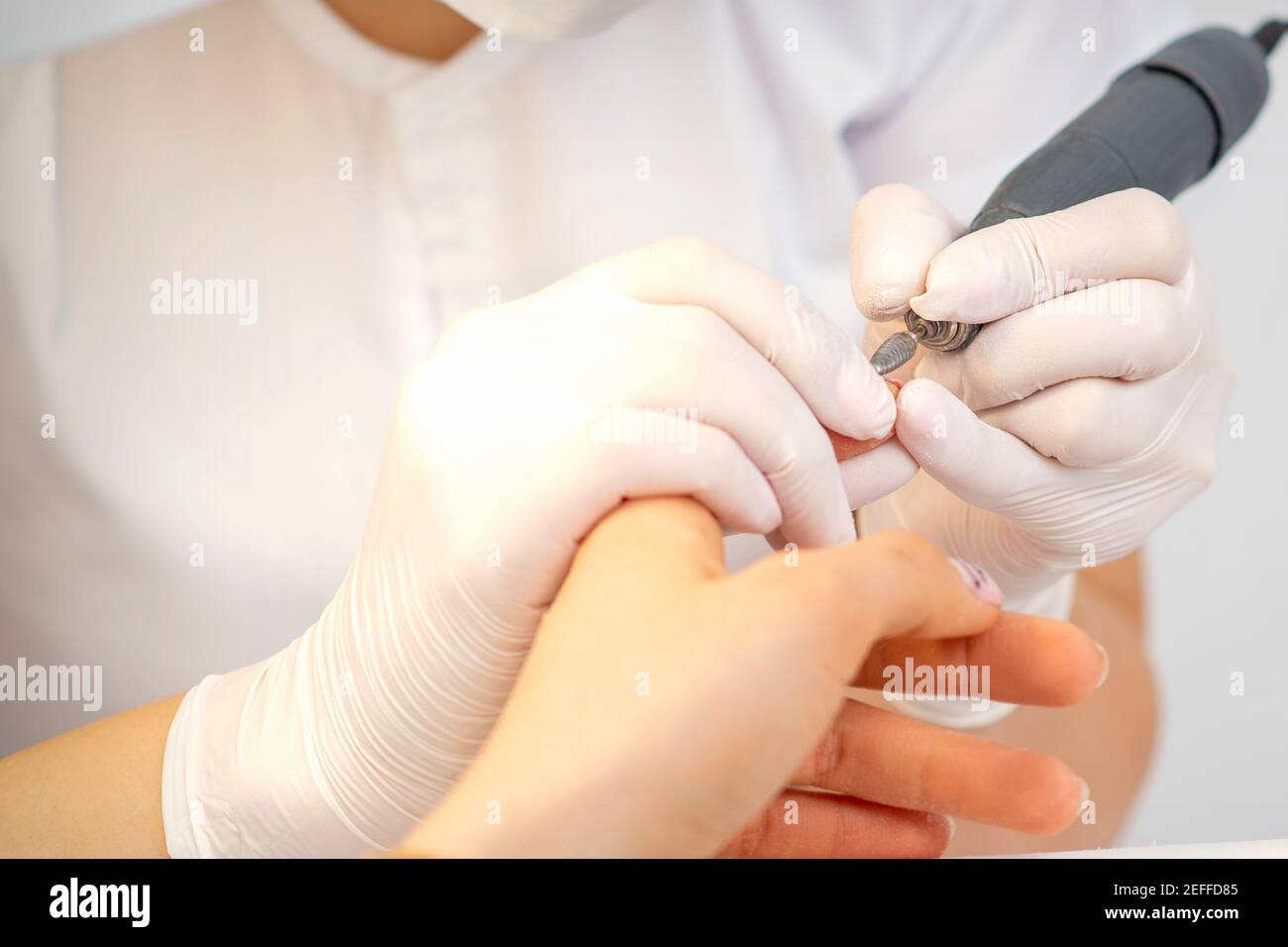 Closeup of manicure master removes nail polish uses an electric nail ...