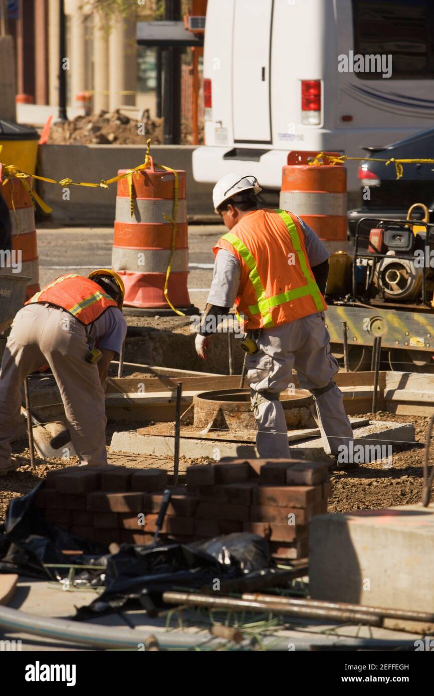 Rear view of two construction workers working at construction site hi ...