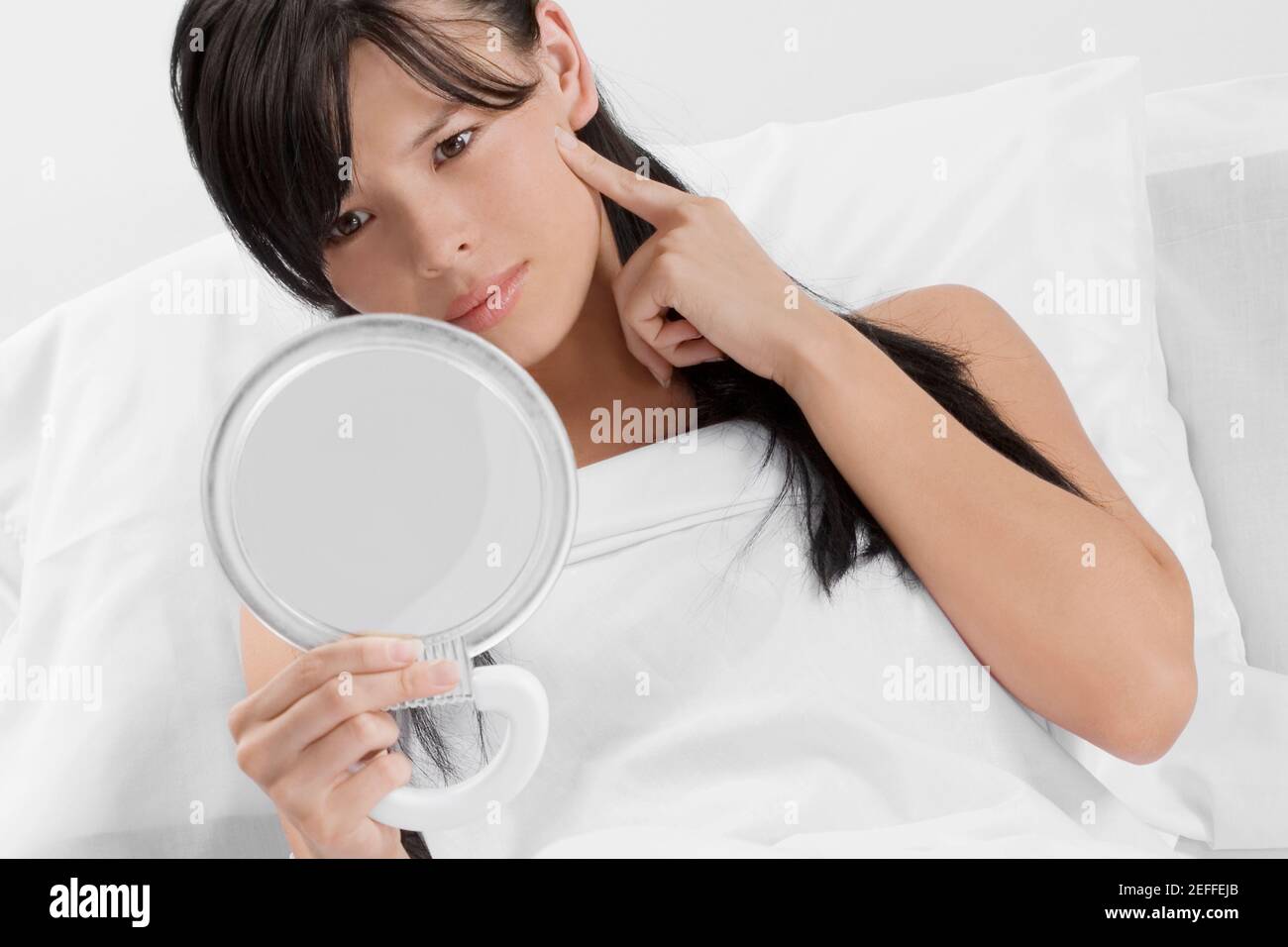 Female patient examining her face in a mirror Stock Photo - Alamy