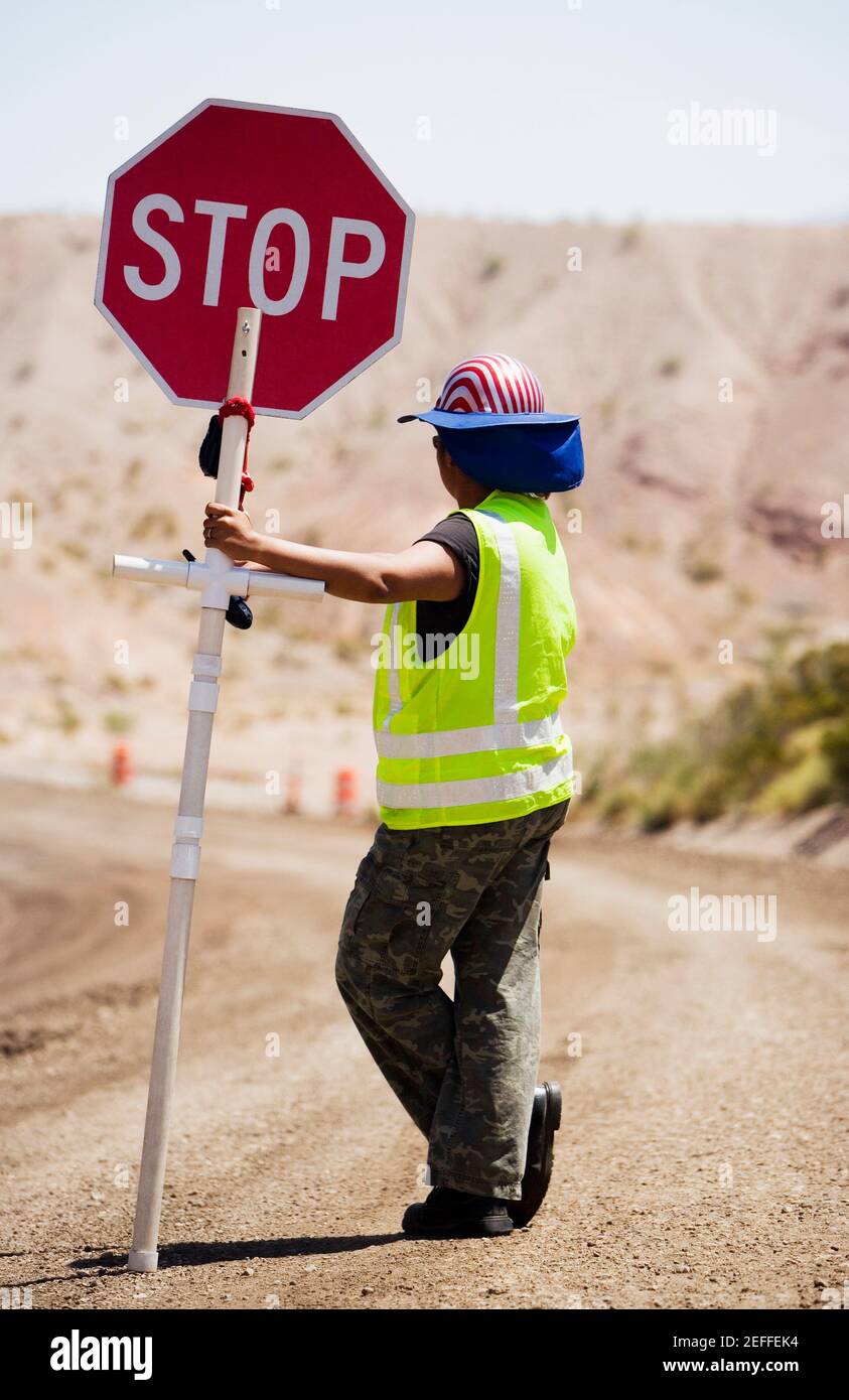 Side profile of a man holding a stop sign on a dirt road Stock Photo ...