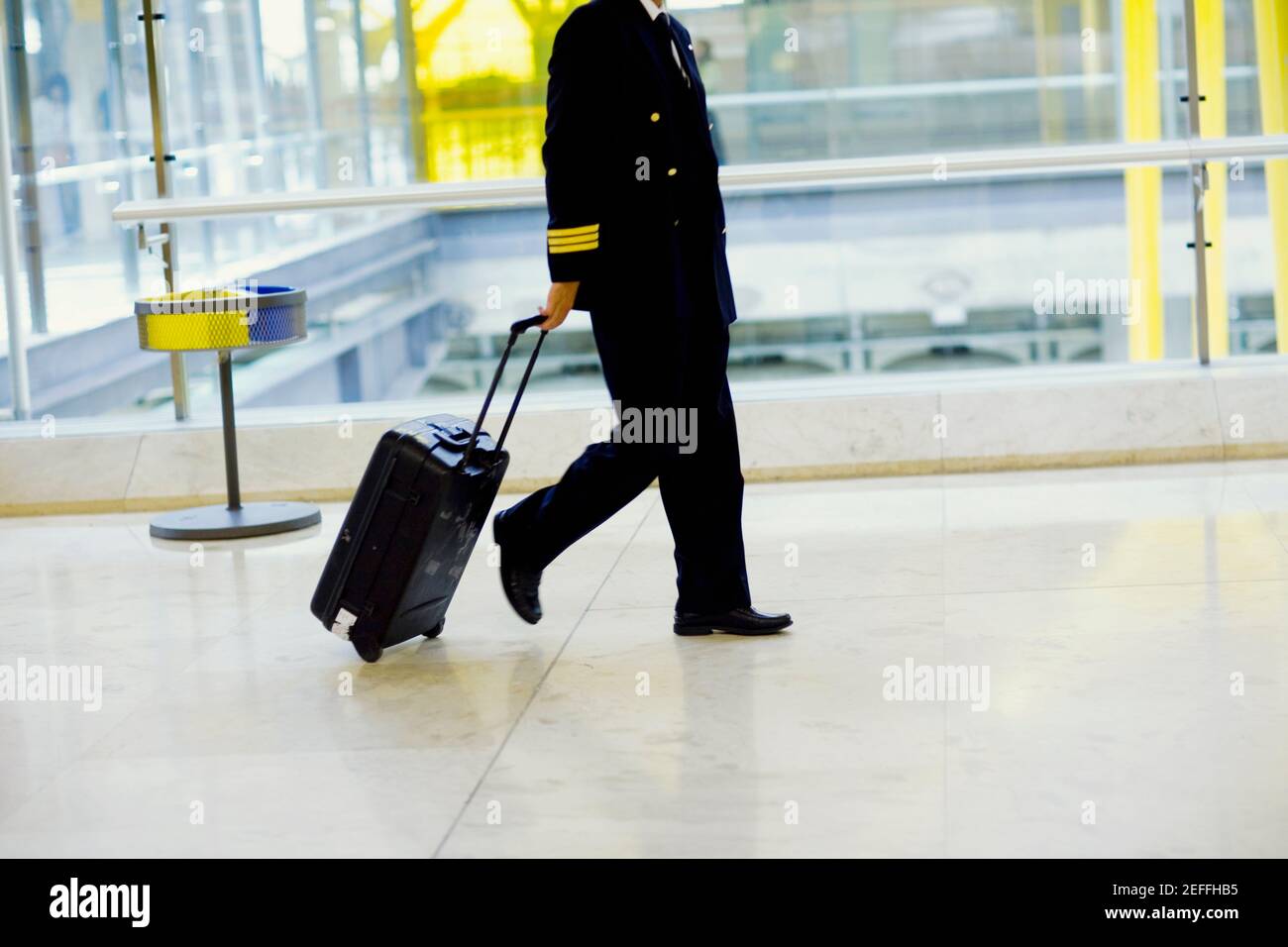 Side profile of a pilot pulling luggage at an airport, Madrid, Spain ...