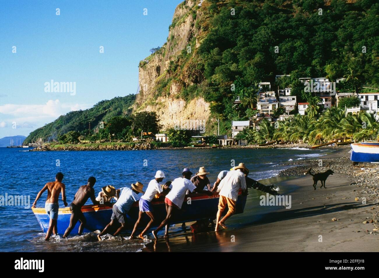 Natives pushing a boat onto a shore near the town of Castries, St ...