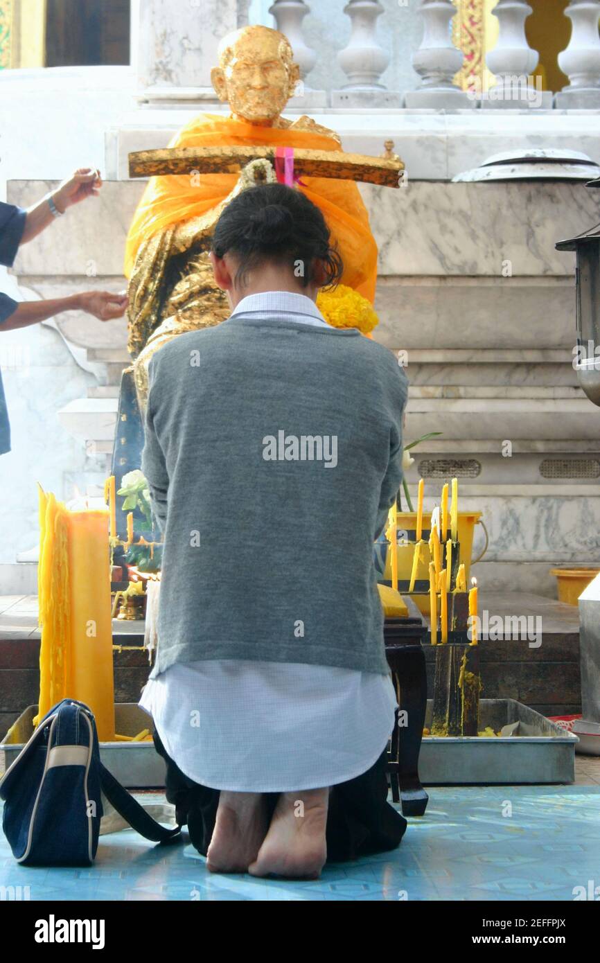 Rear view of a woman praying in front of a statue, Ko Ratanakosin ...